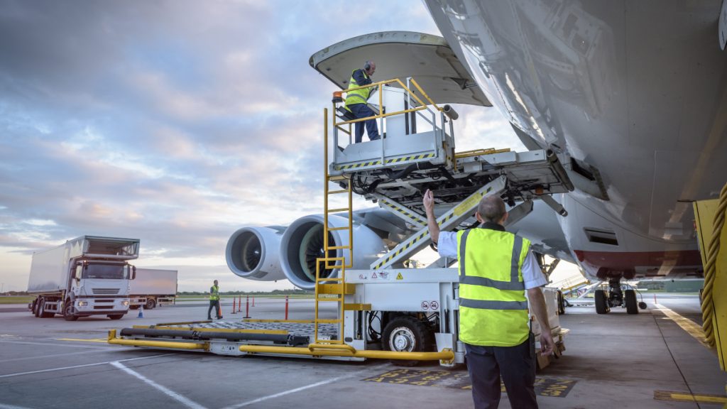 Ground crew attending to A380 aircraft with freight loader at airport ...